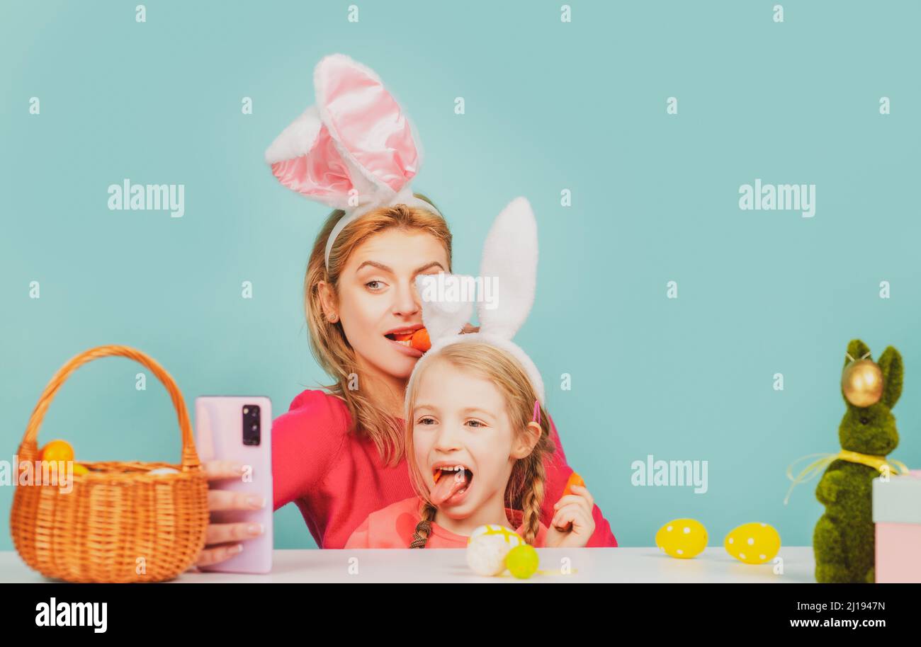 Easter. Funny bunny girls eating carrot. Mom and daughter wearing bunny ...