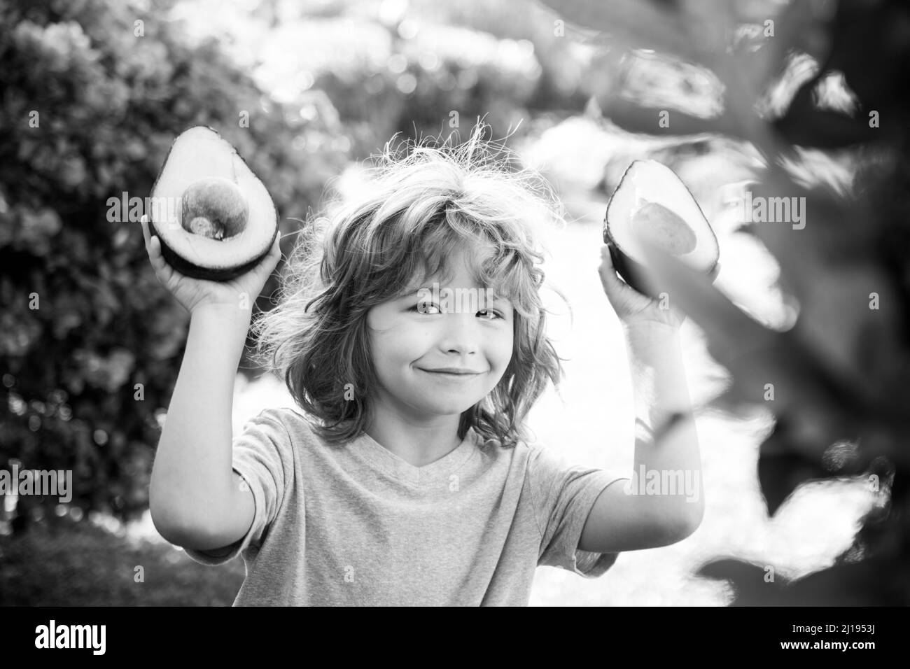 Kid eating and enjoying an avocado on a nature background. Healthy food ...