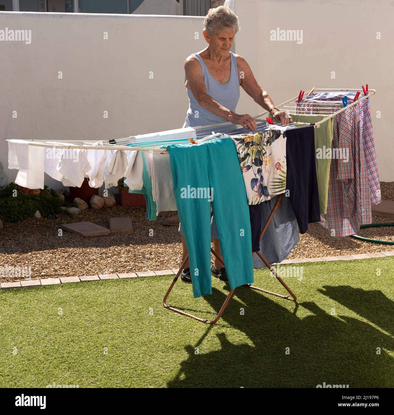South Africa. 2022. Elderly woman hanging washing out to dry in the ...