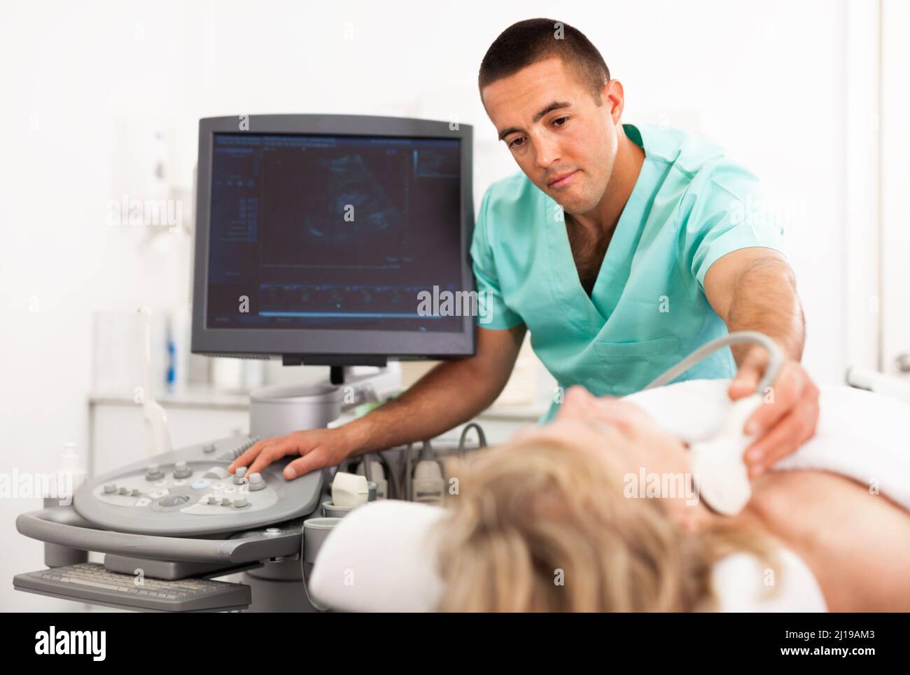 Young man sonographer using ultrasonography machine checking female ...