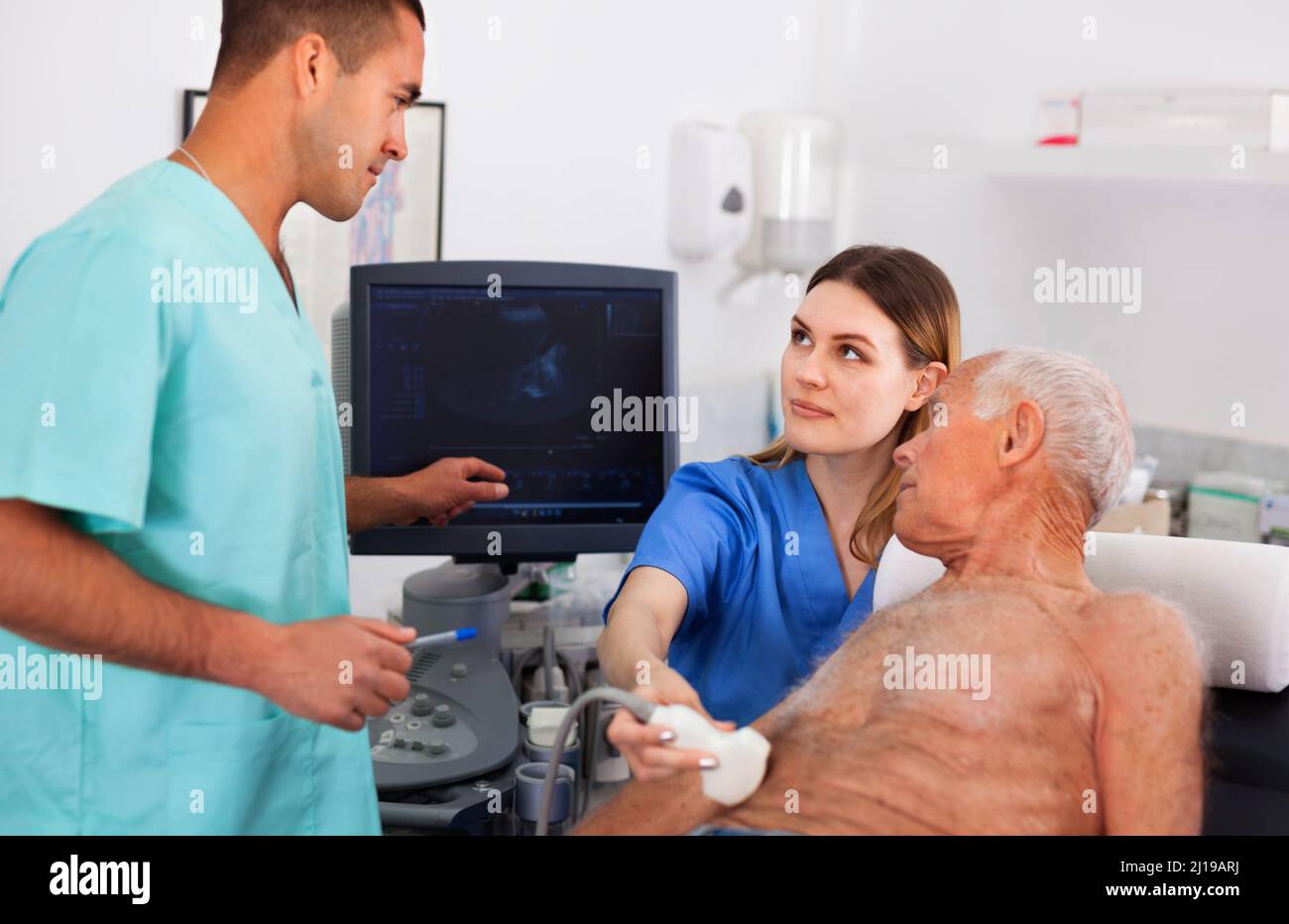 Skilled doctor with assistant diagnosing patient using ultrasonography ...