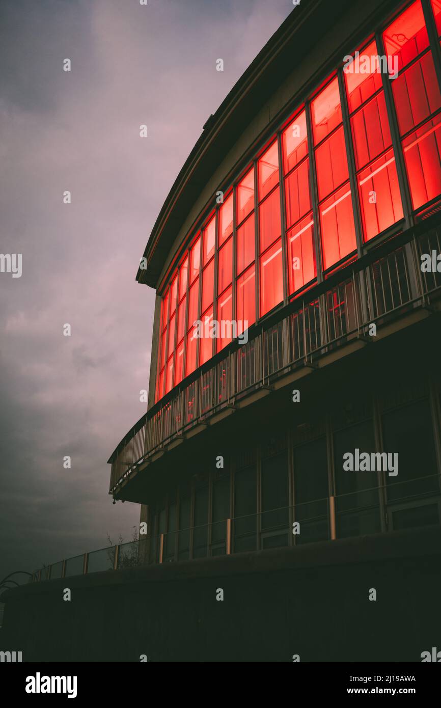 A low angle shot of glowing red glass windows of the building's second ...