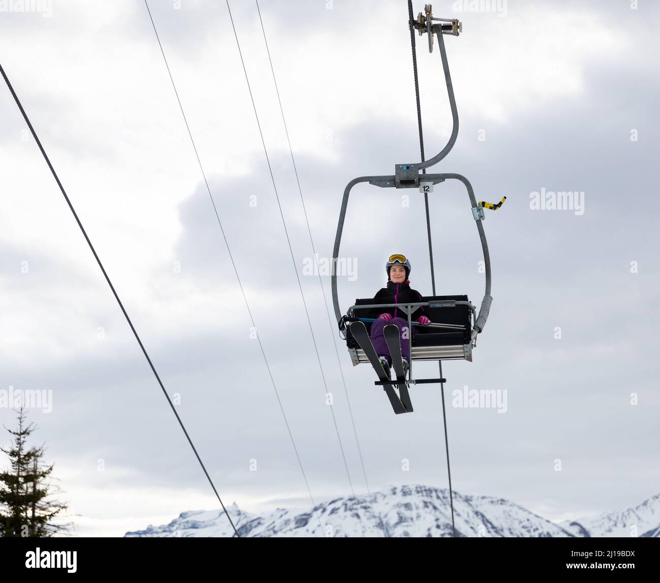 Woman skier riding on chairlift on background of snowy mountains Stock ...