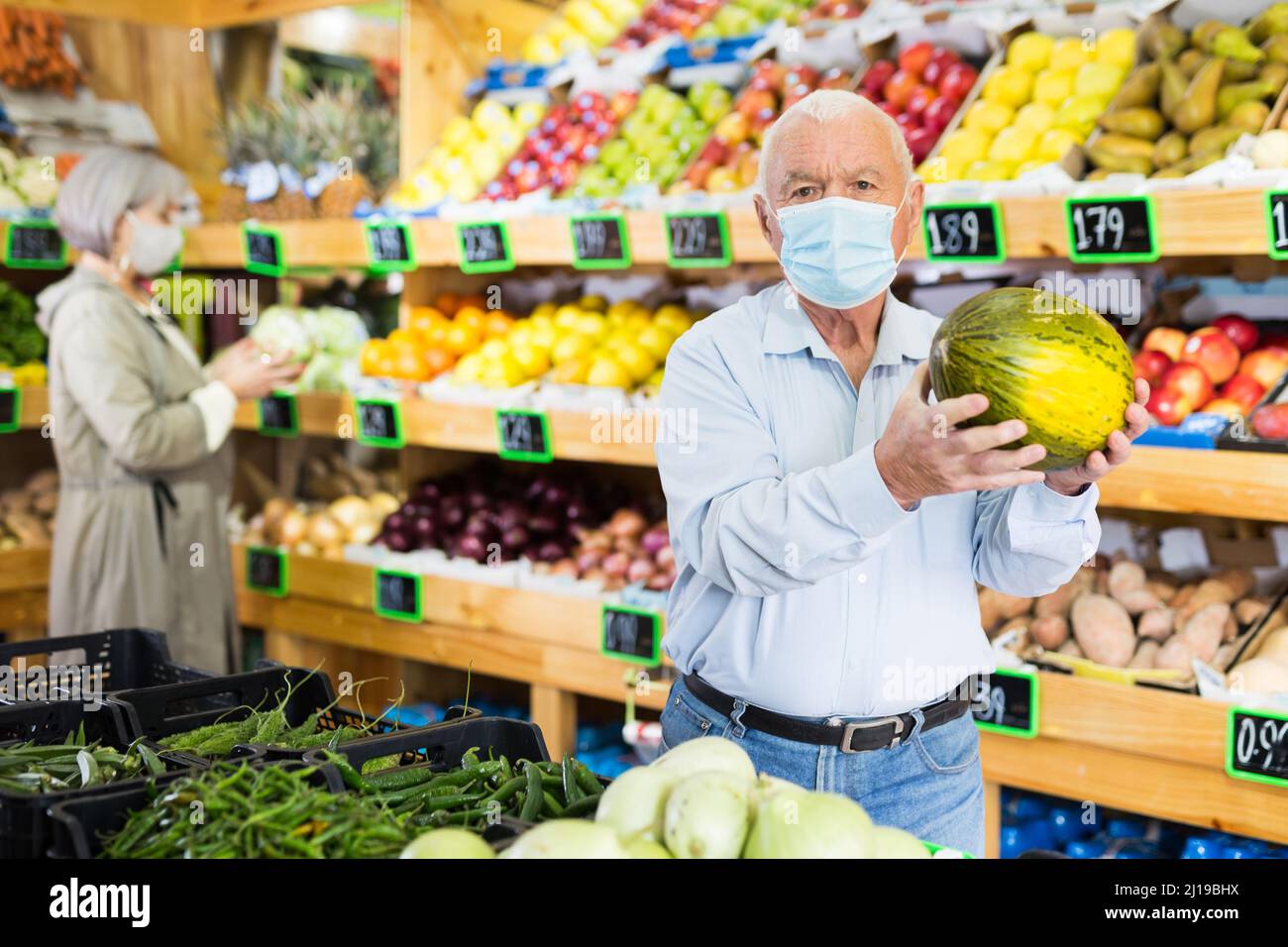Senior man in mask choosing melon in greengrocer Stock Photo - Alamy