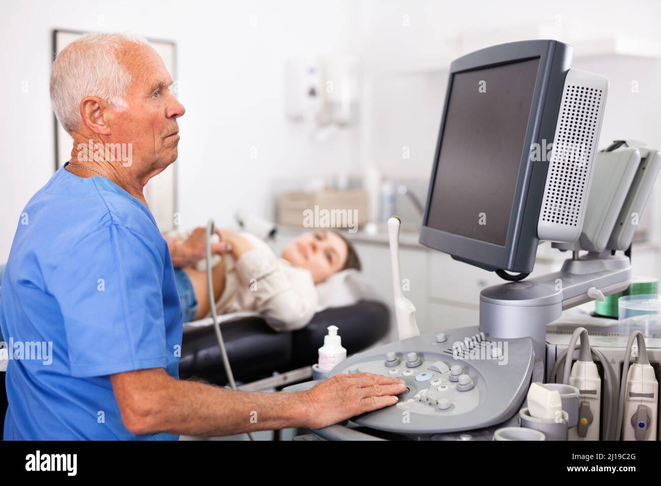 Elderly man sonographer using ultrasonography machine checking female ...