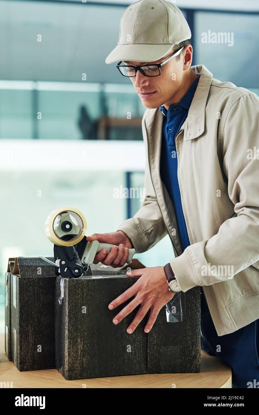 Sealing the last of his boxes for delivery. Shot of a delivery man ...