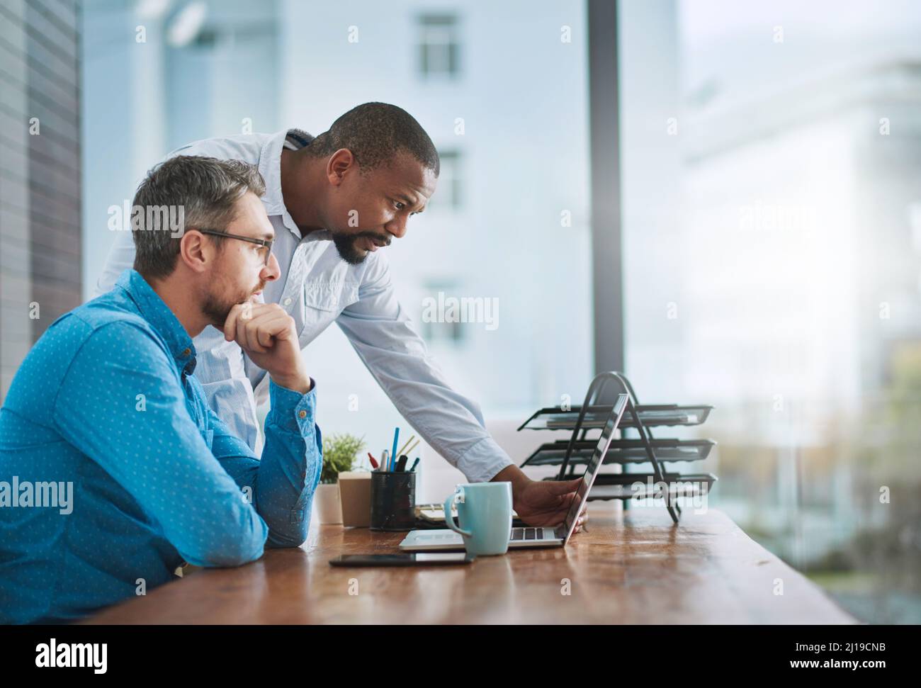 Let me take a look.... Shot of two businessmen working on a laptop in ...