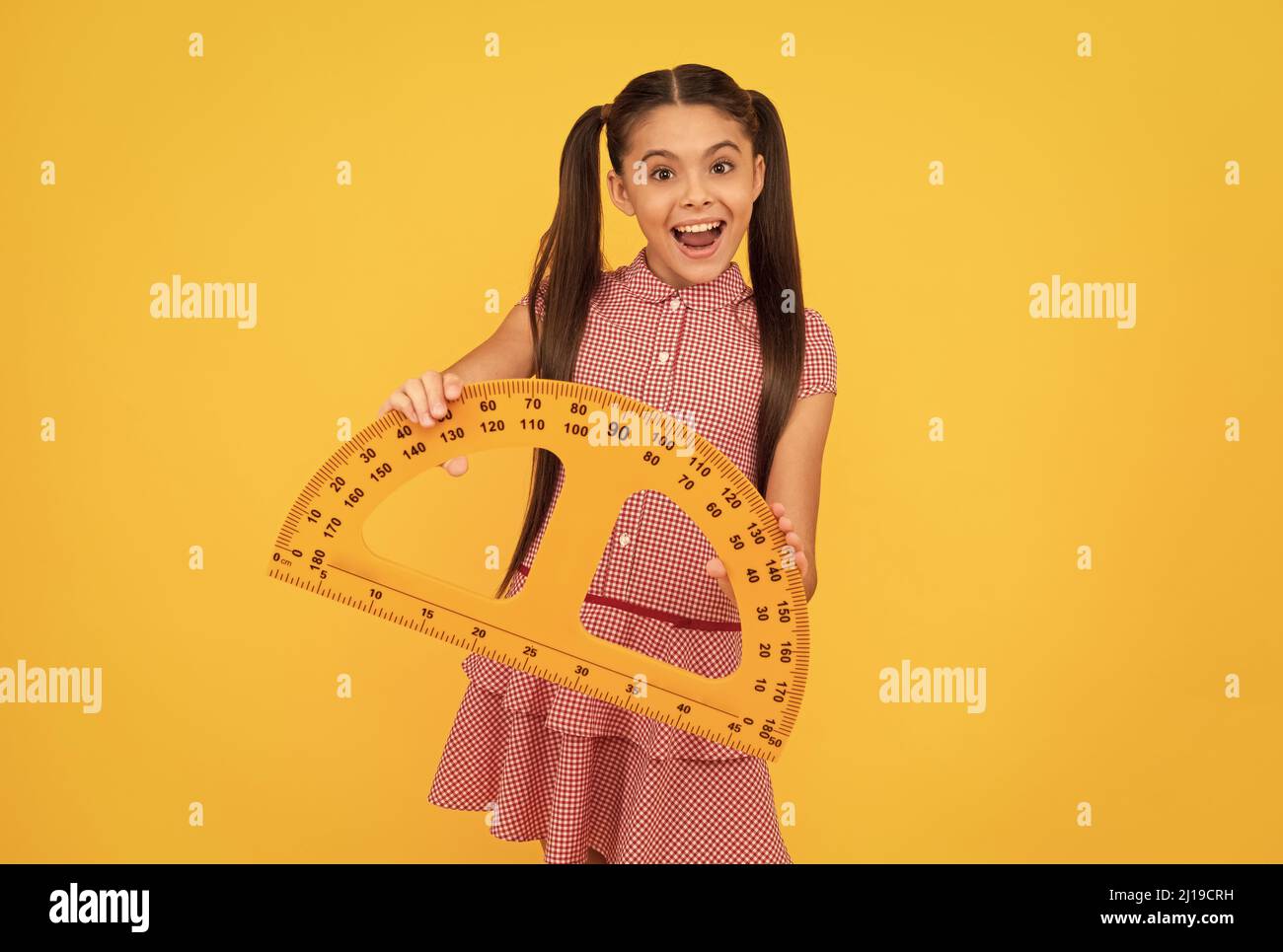 amazed kid hold school math tool protractor ruler on yellow background ...