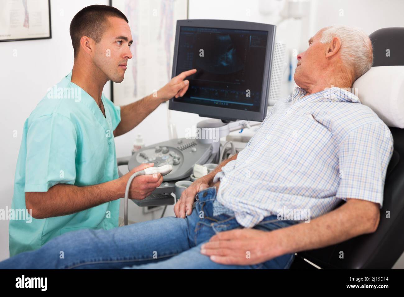 Doctor pointing to monitor during examination a man with ultrasound ...