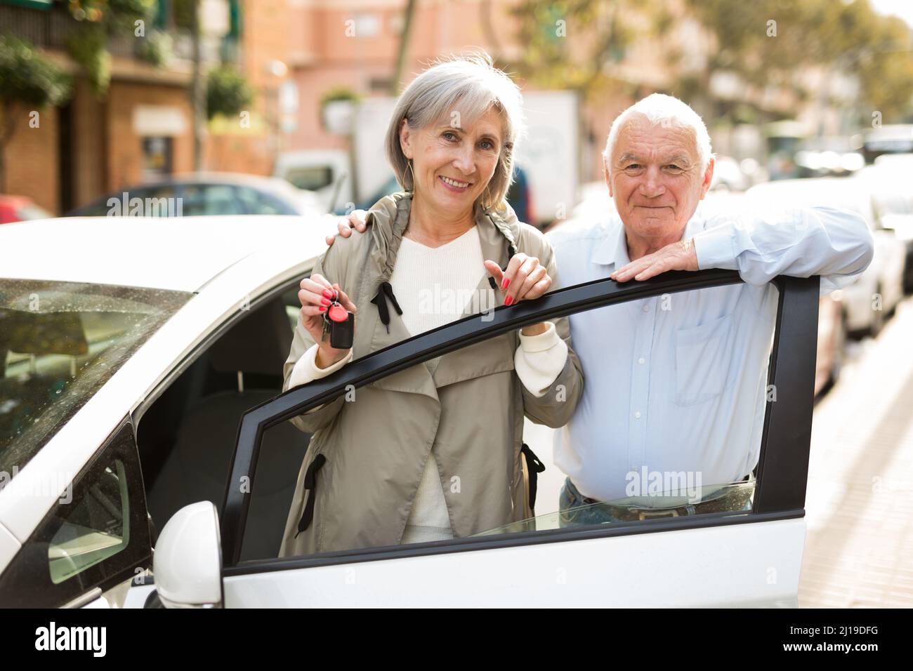 Happy married couple next to a new car on street Stock Photo - Alamy