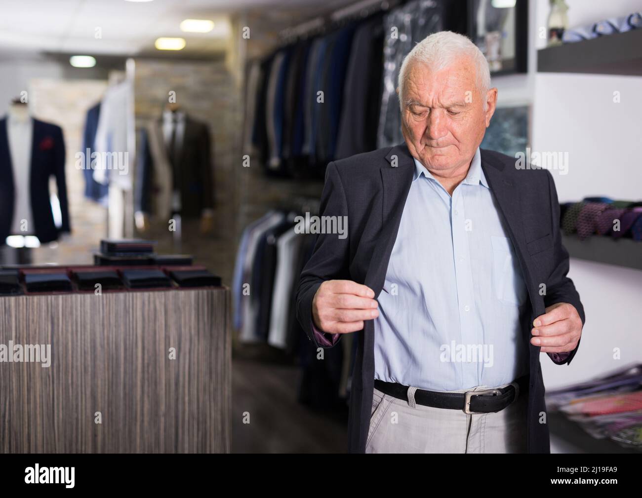 Senior customer trying on a fashion jacket in the men boutique Stock ...