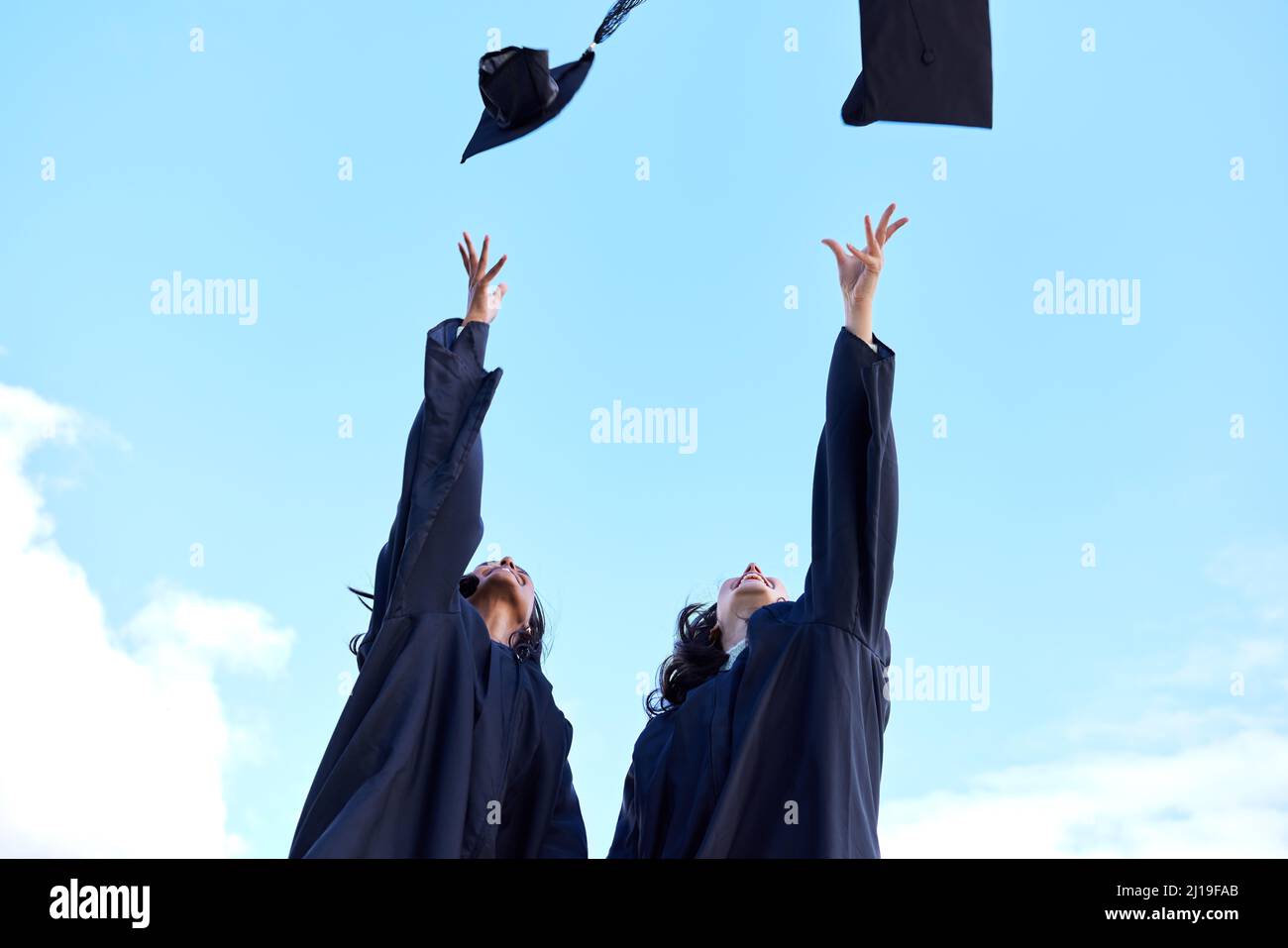 The famous graduation day tradition. Low angle shot of two attractive ...