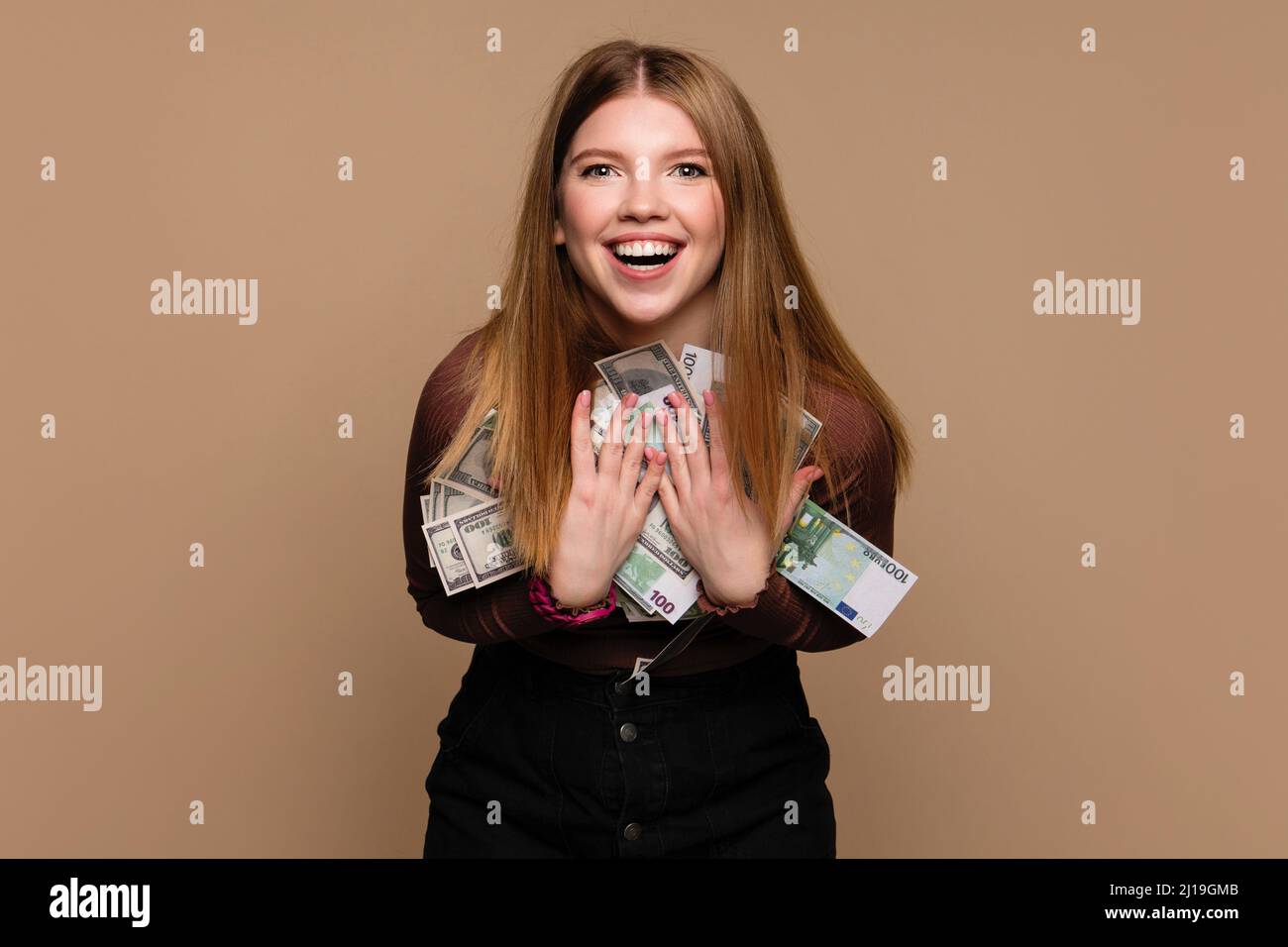 Pleasantly shocked girl hugging bunch of paper money. Female holding ...