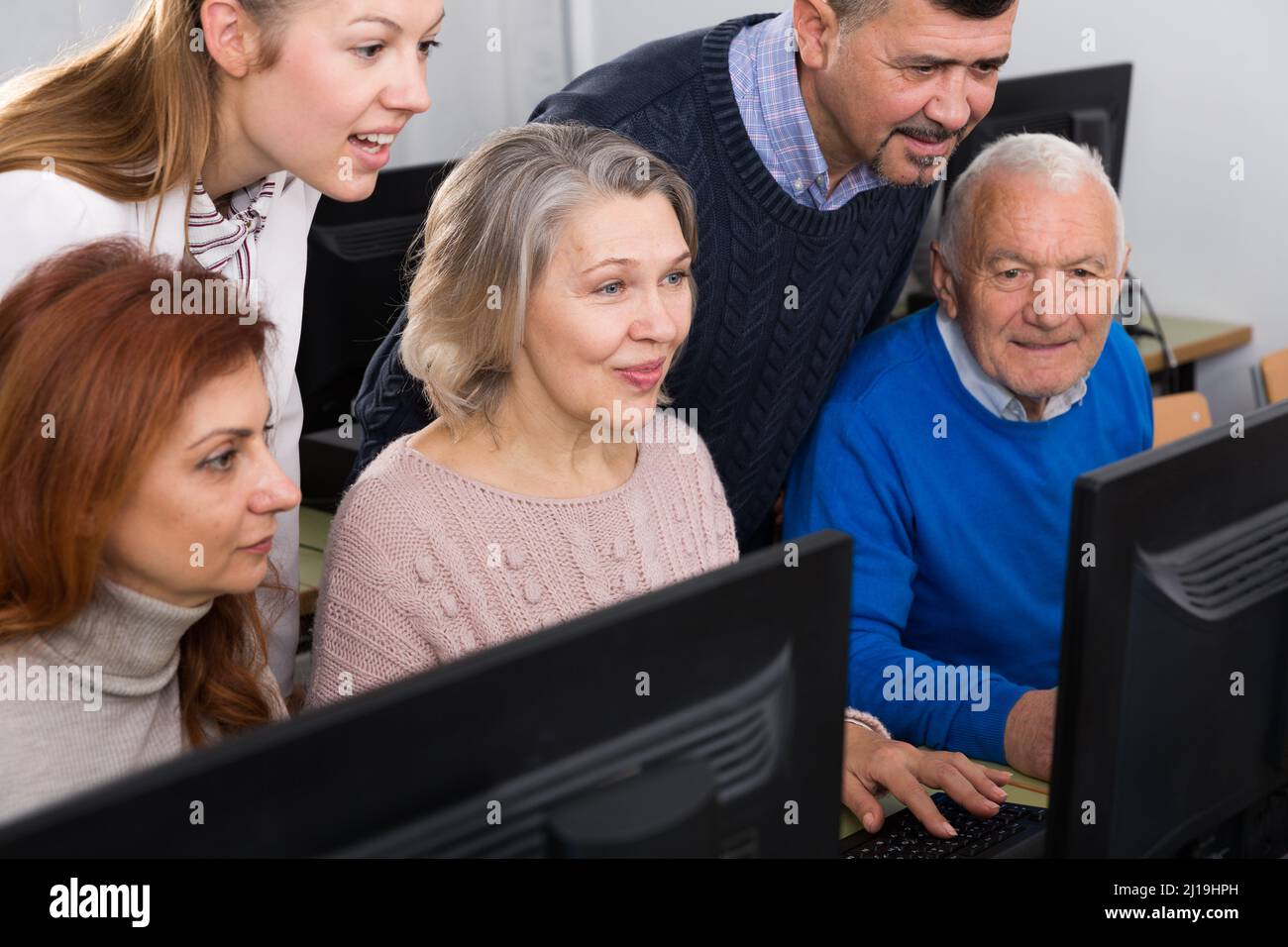 Elderly people working on computer with young teacher Stock Photo - Alamy