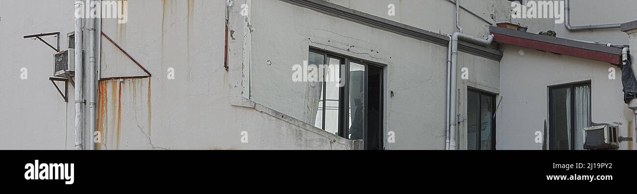 White cracking building exterior with old pvc gutters, rust stain and ...