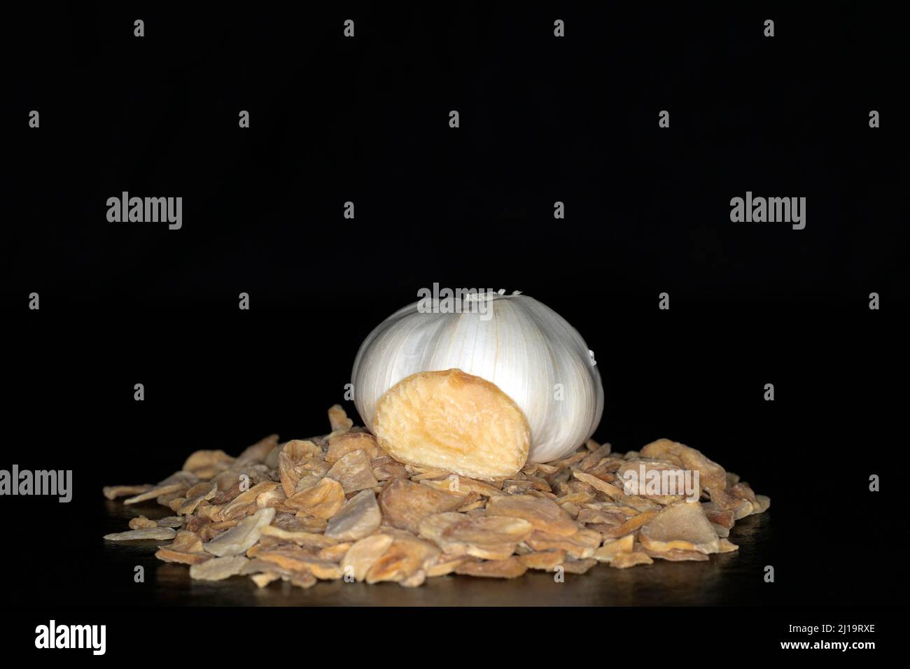 Fresh garlic bulb lying on dried garlic slices, studio photography with ...