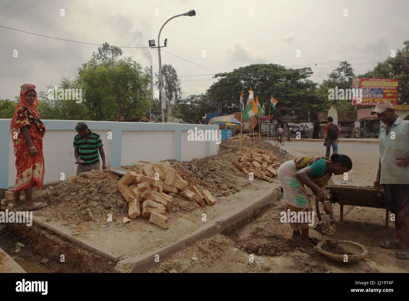 Women working manual labour at a roadside construction site in Kolaghat ...