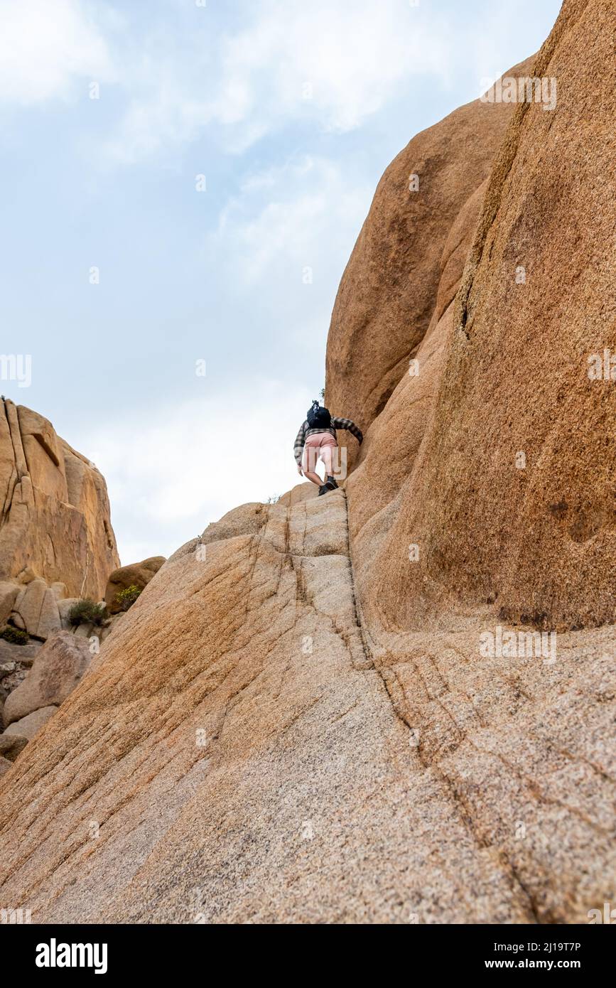 Man hiking up large rock boulders in the California desert Stock Photo ...