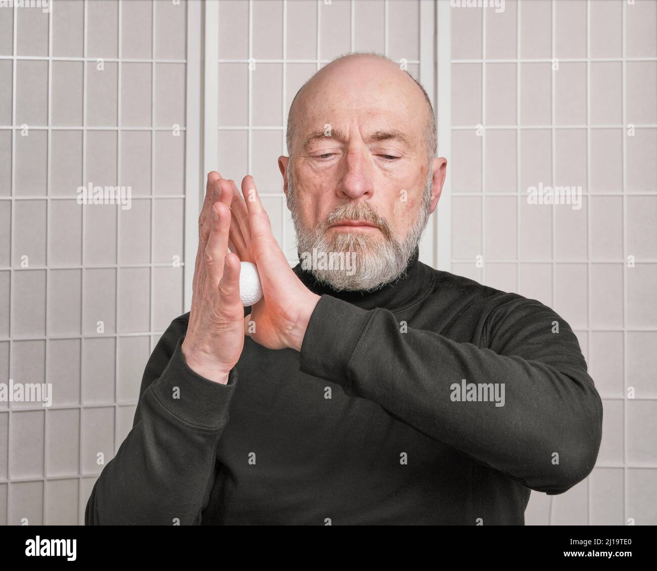 senior man is practicing reflexology therapy by rolling and pressing a ...
