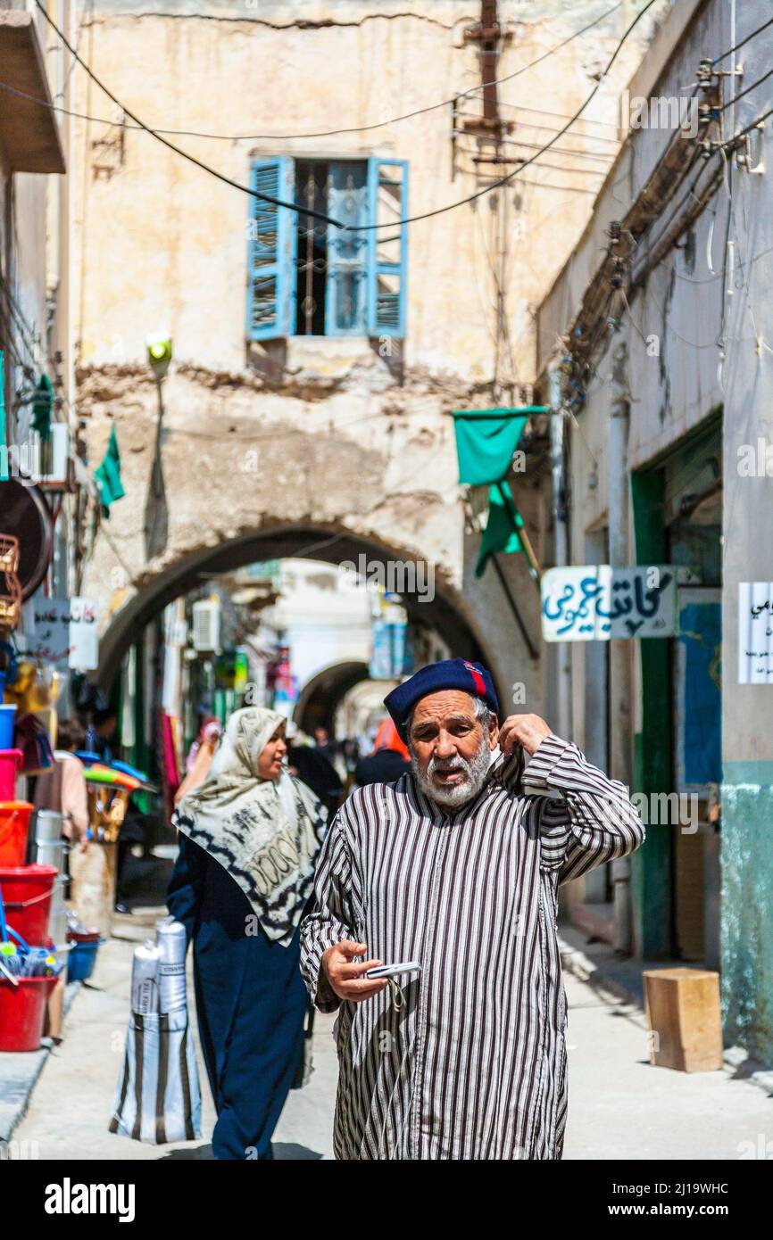 An elderly man in traditional attire walking through the streets of the ...