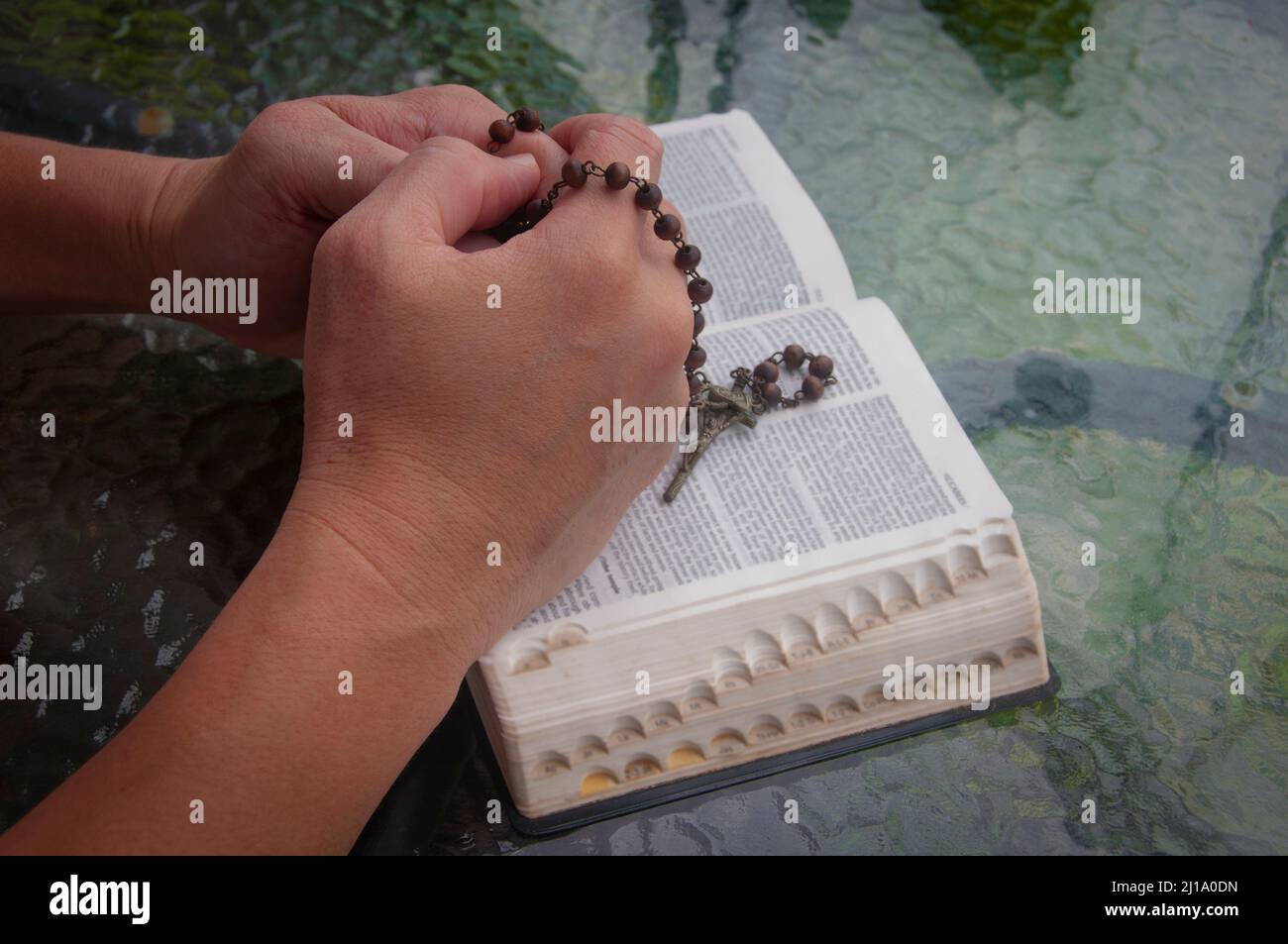 Hand holding Rosary on a Holy Bible while praying. Christianity and ...