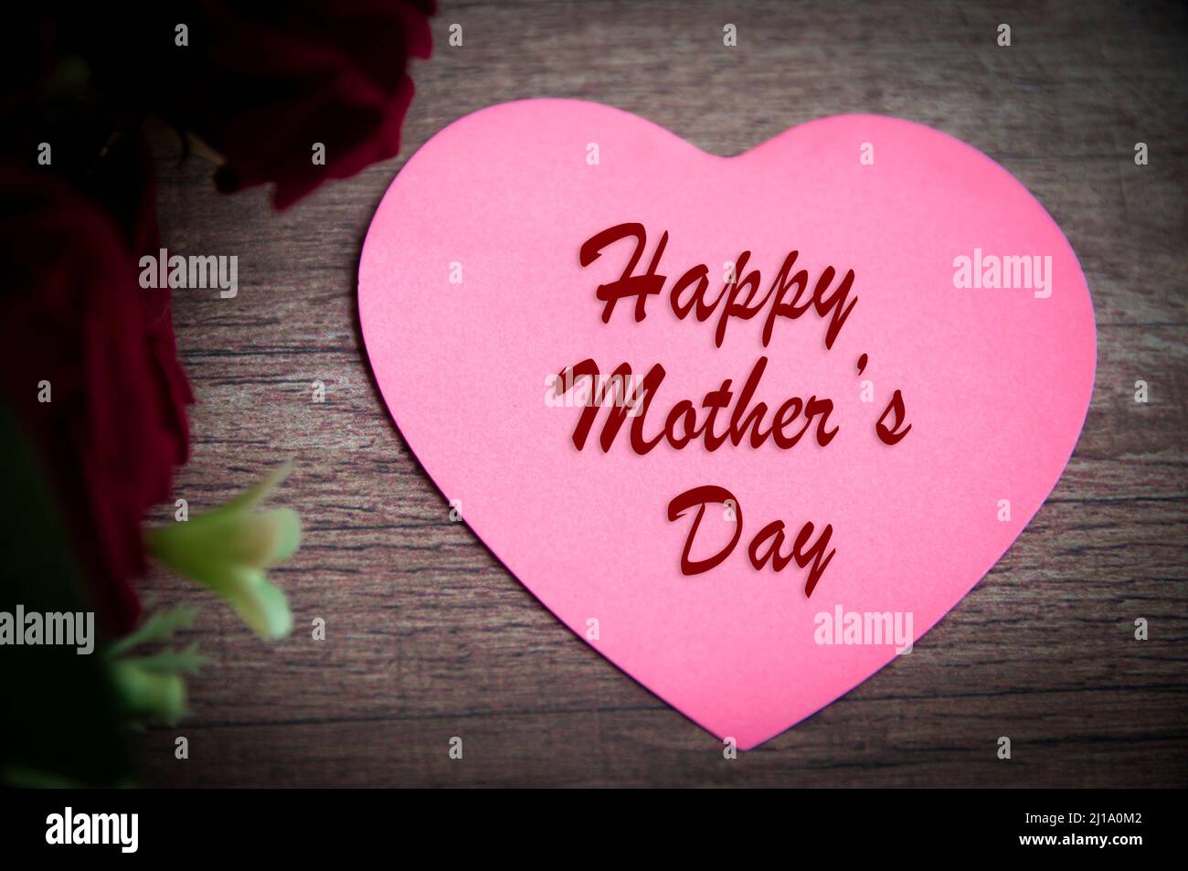 Happy mother's day text on heart shape sticky note. Roses and wooden ...