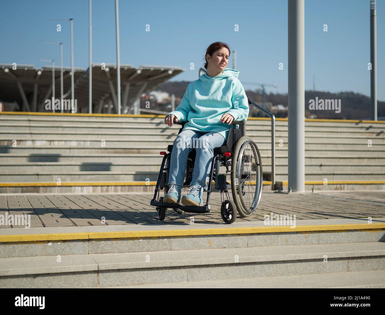 A caucasian woman in a wheelchair cannot go down stairs without a ramp ...