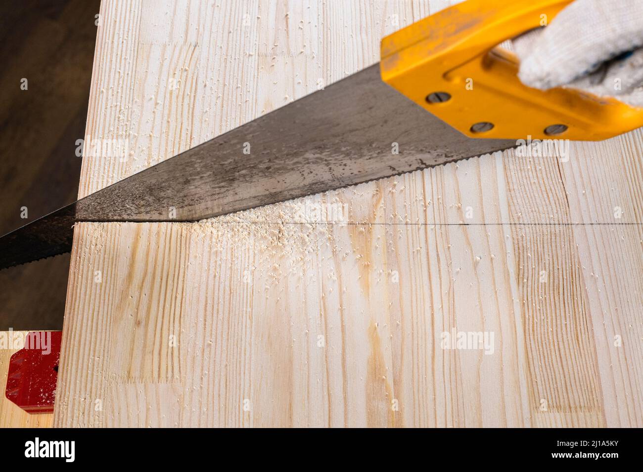 pov view of sawing wooden board with hand saw on workbench at home ...