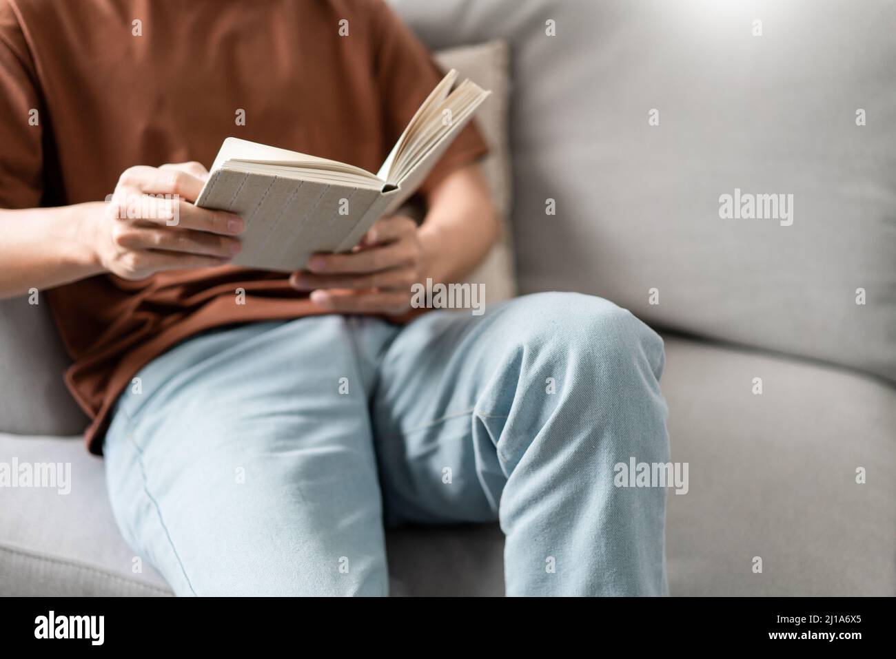 Technology Concept The male with his glasses sitting on the grey sofa ...