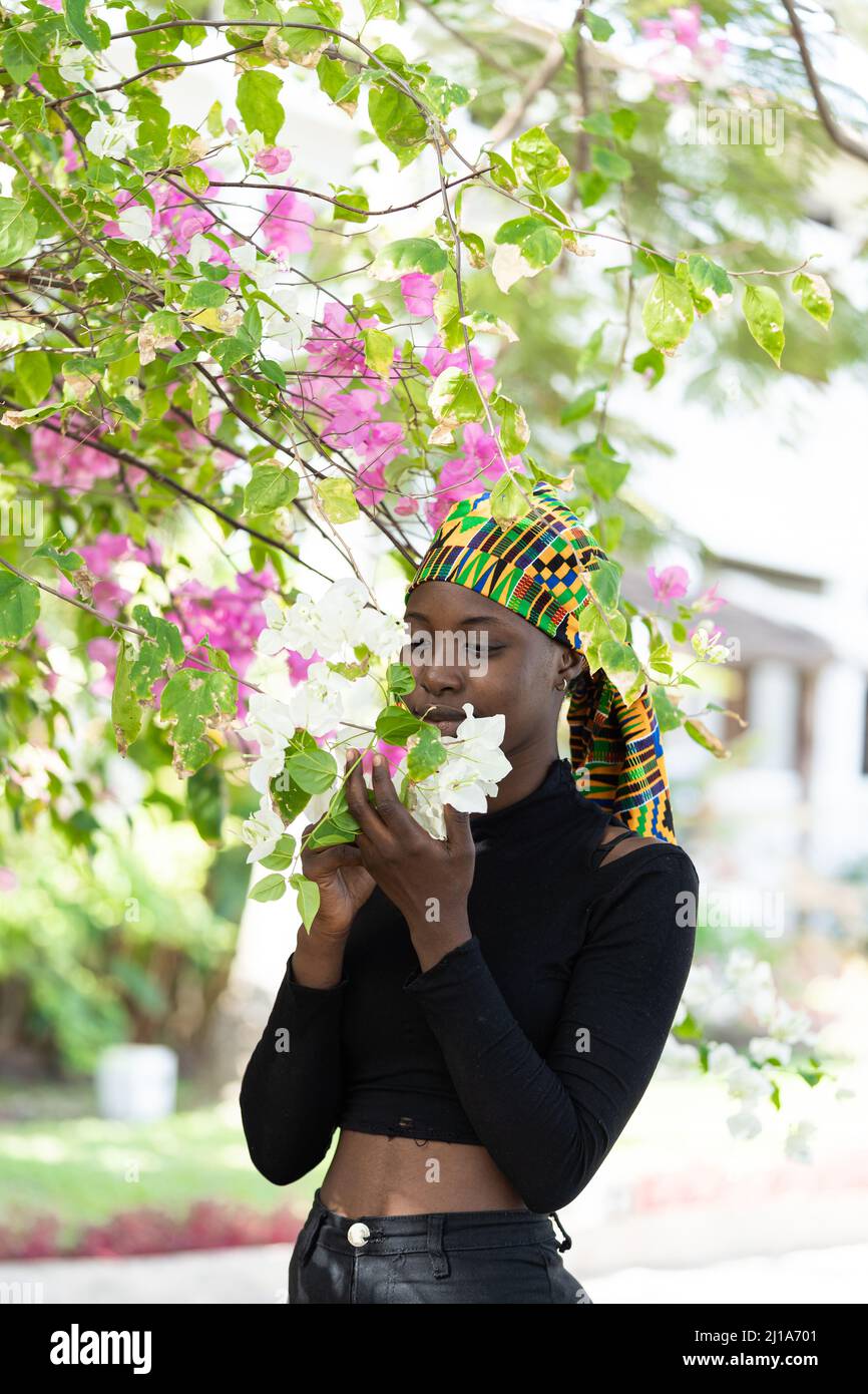 Charming young African woman softly caressing the delicate flowers of a ...