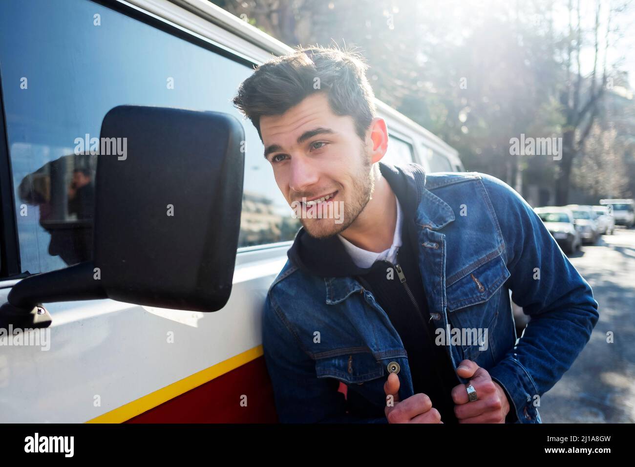 Young male is pleased to see his handsome looks on the side mirror of a ...
