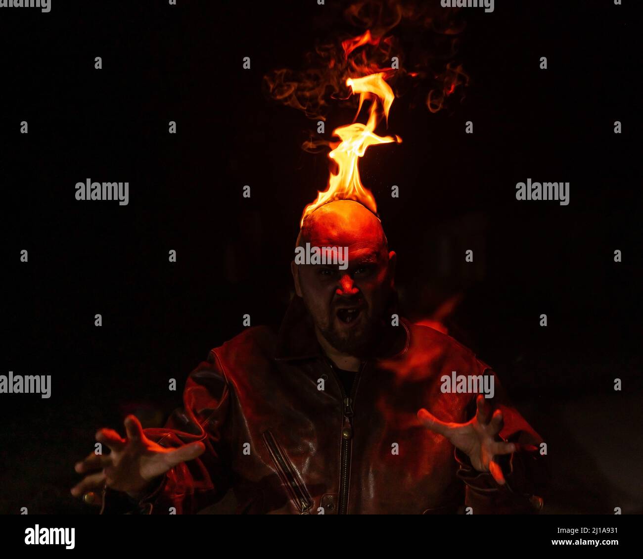 Bald man in a leather jacket with a burning head on a dark background ...