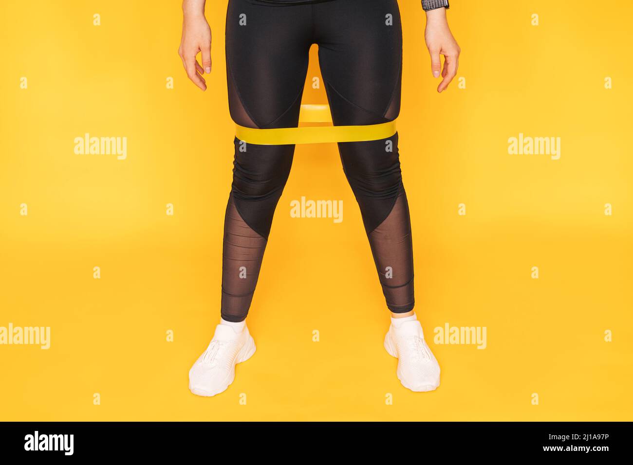 Girl in leggings with an elastic band on her legs against yellow ...