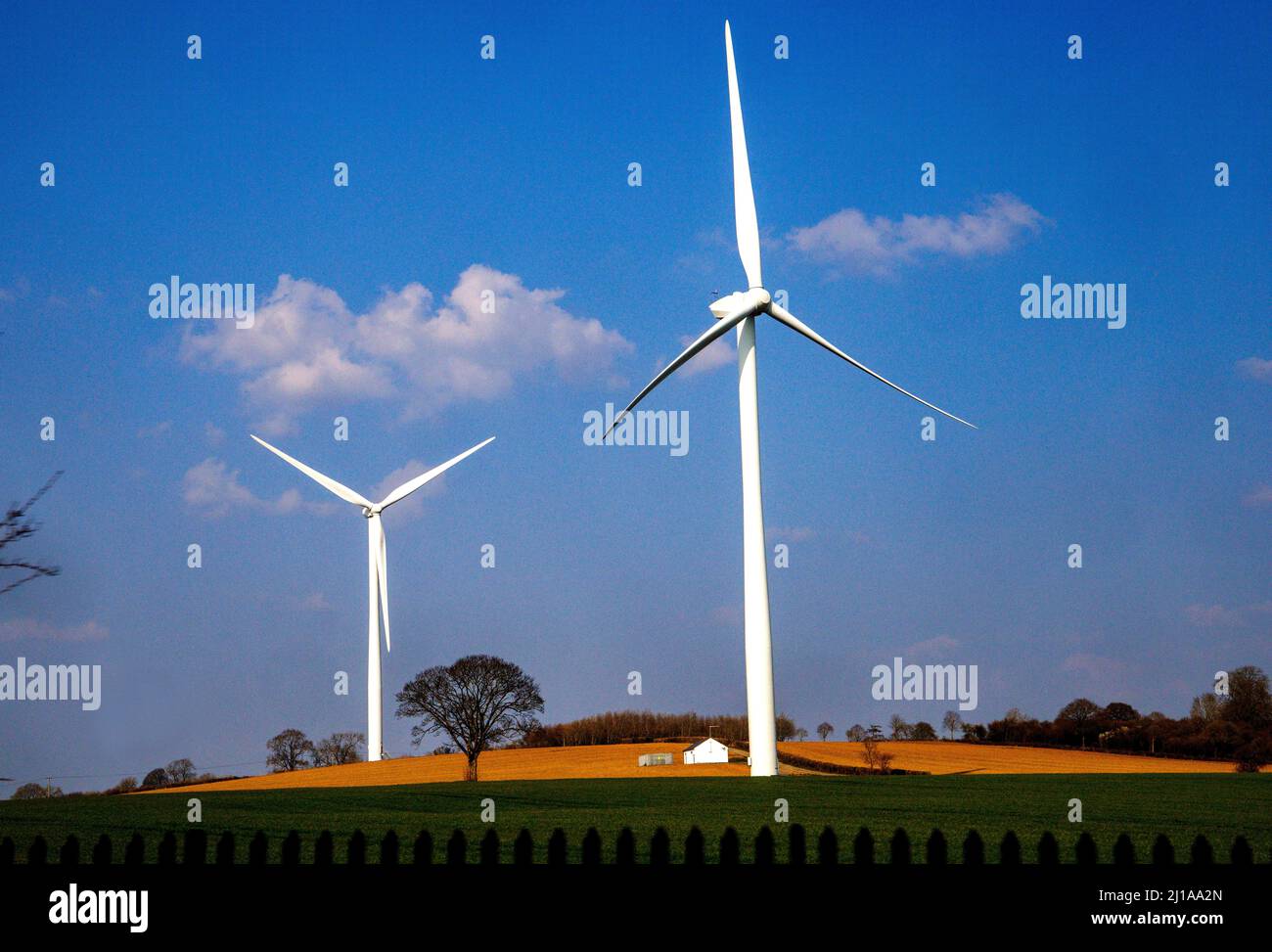 Two wind turbines in the English landscape. They convert kinetic energy ...