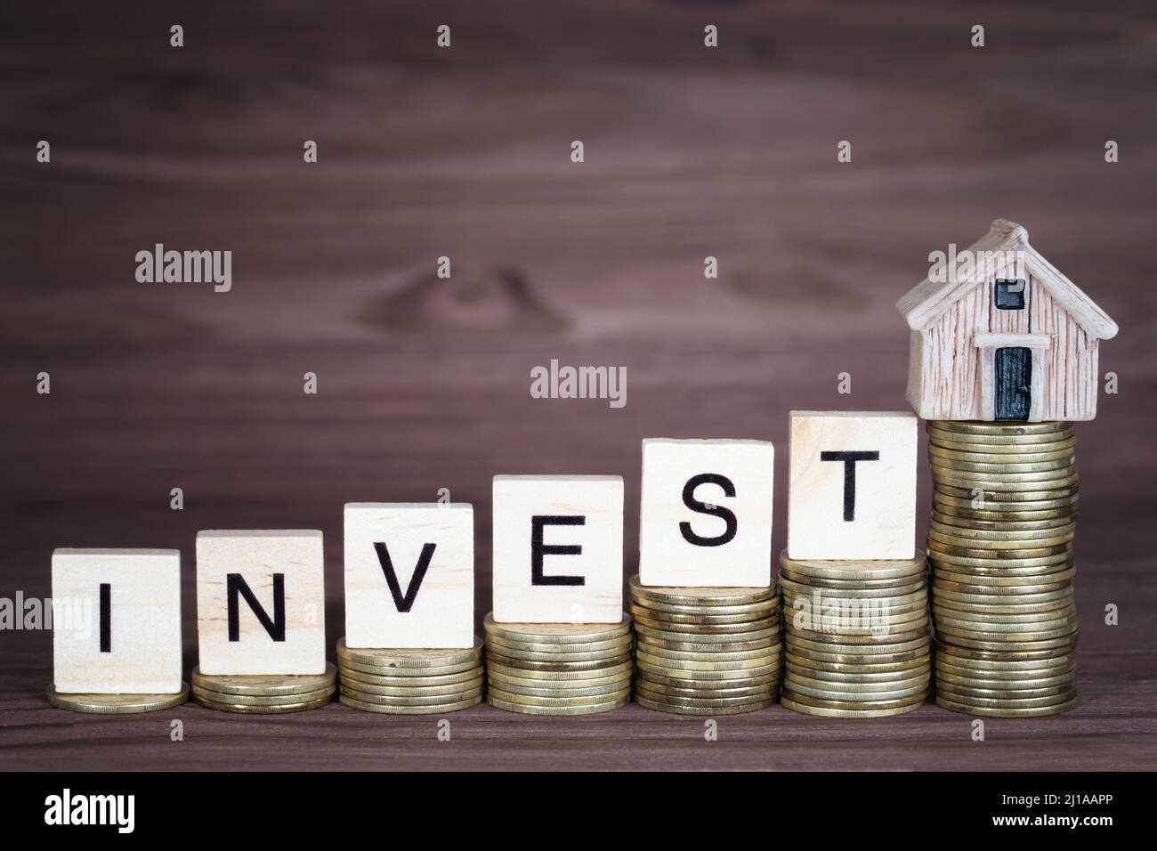 Word INVEST made from wooden letter blocks and a miniature house placed ...