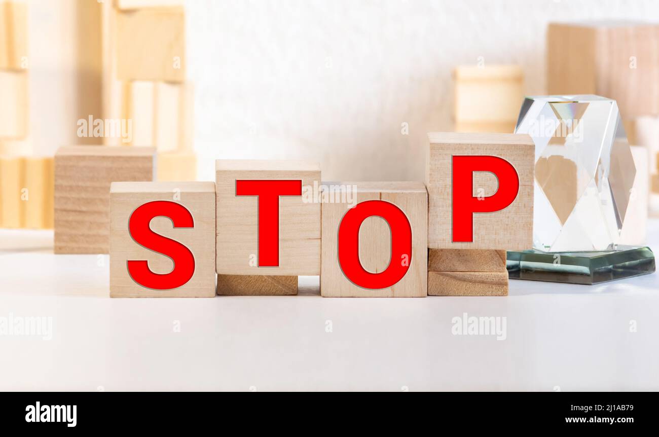 STOP word concept written on wooden cubes blocks lying on a light table ...