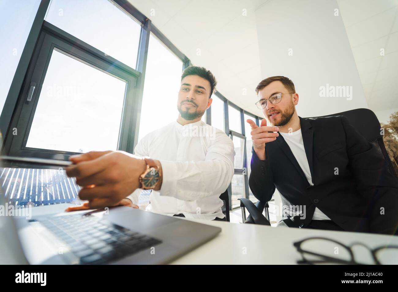 Two multiethnic businessmen working on a laptop in the office Stock ...