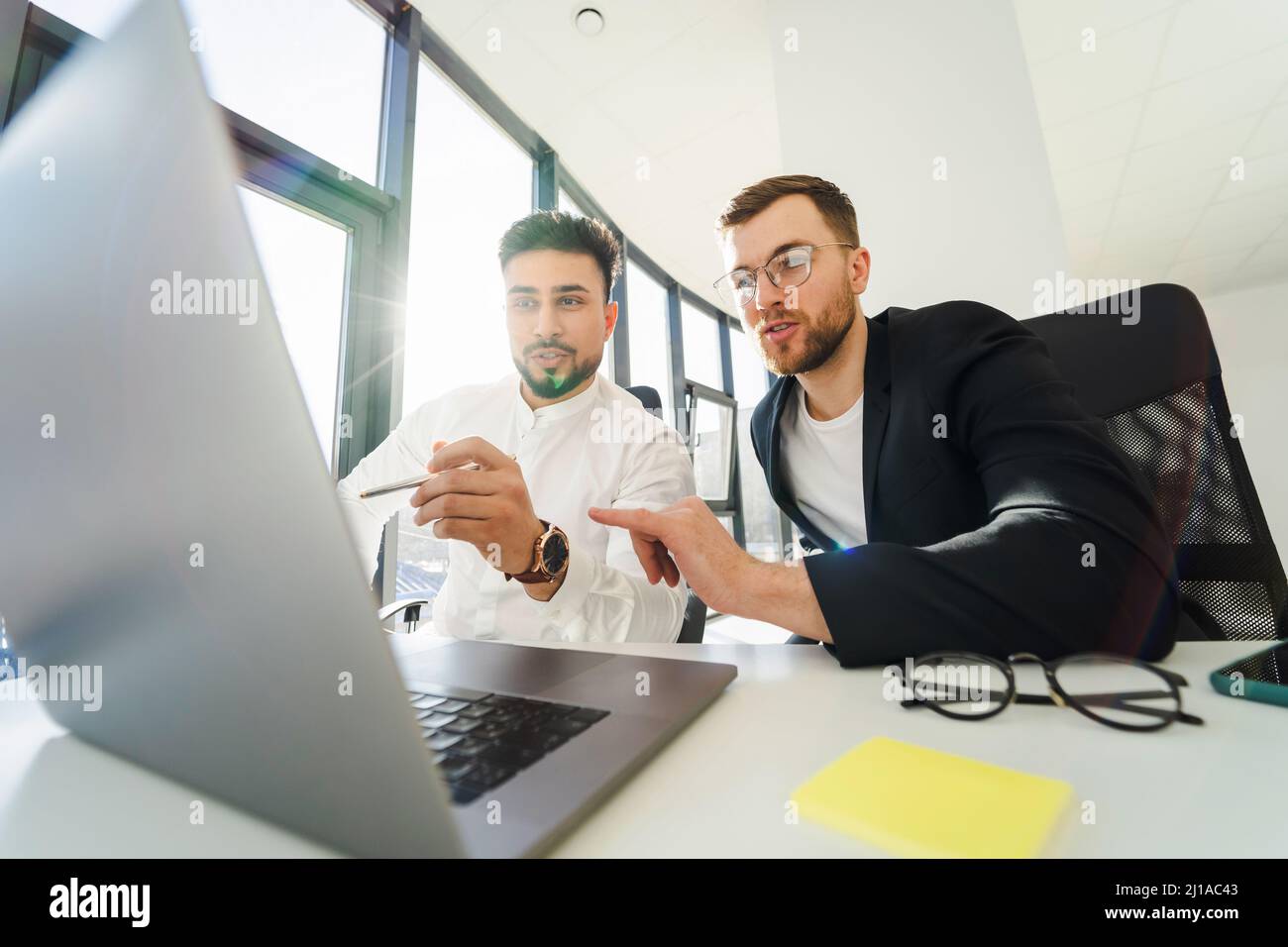 Two male office workers analyze profits on a laptop. Businessmen ...