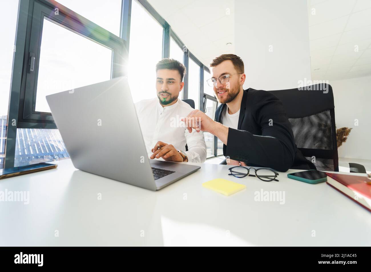 Two multiracial male office workers working on a laptop. IT company ...