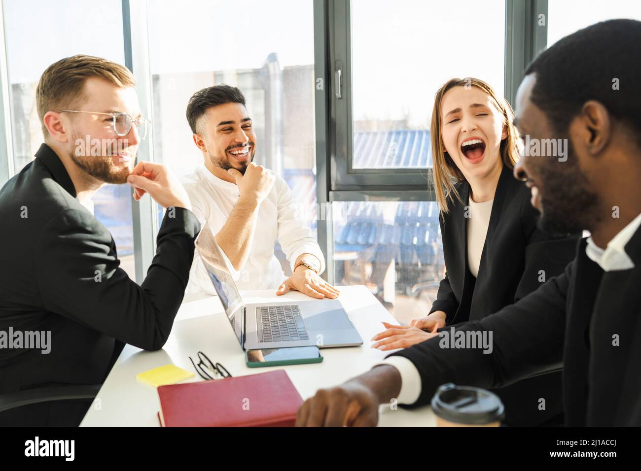Group of laughing corporation employees at a meeting in the office ...