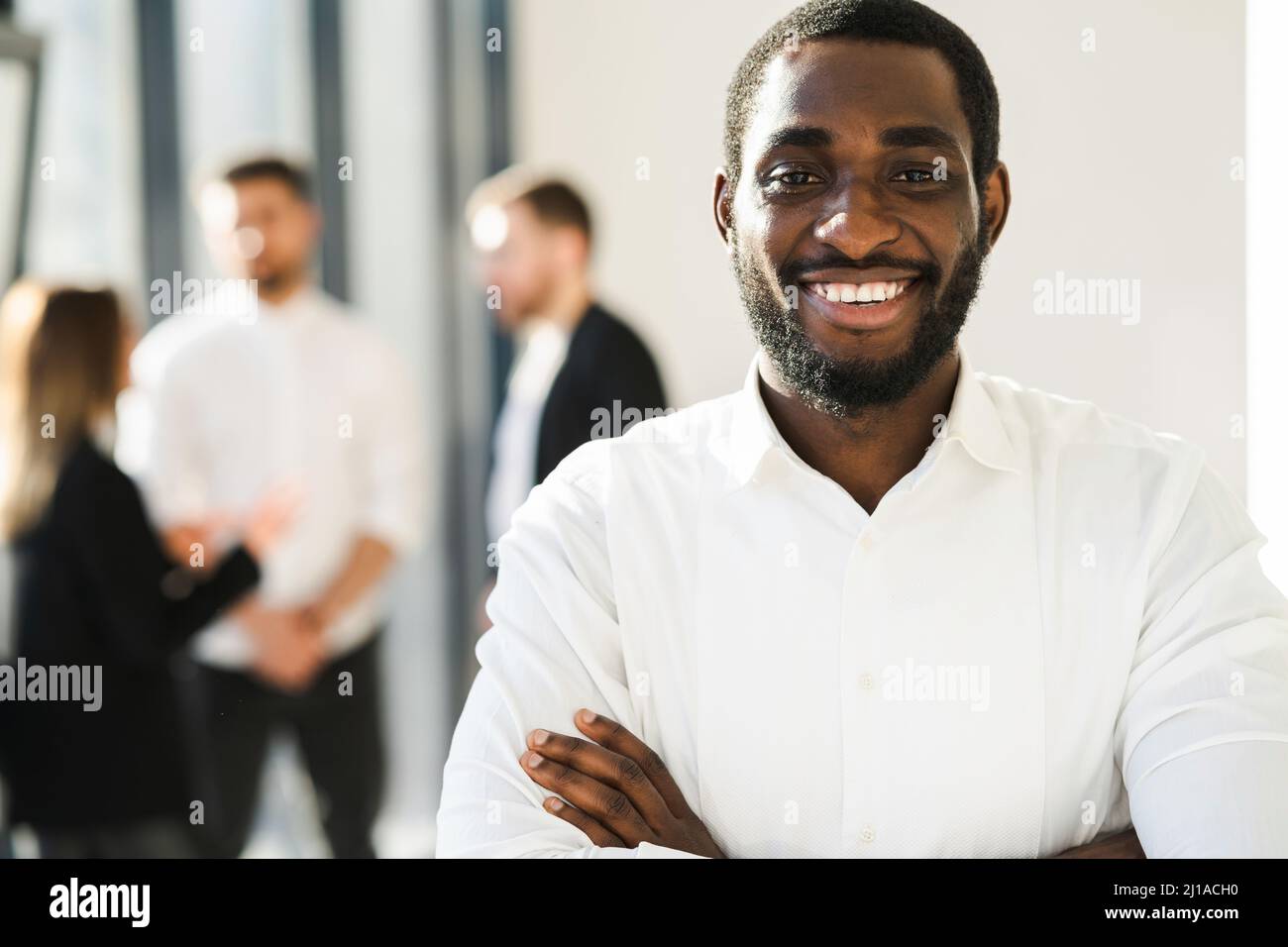 Portrait of a joyful male black company employee with arms crossed ...