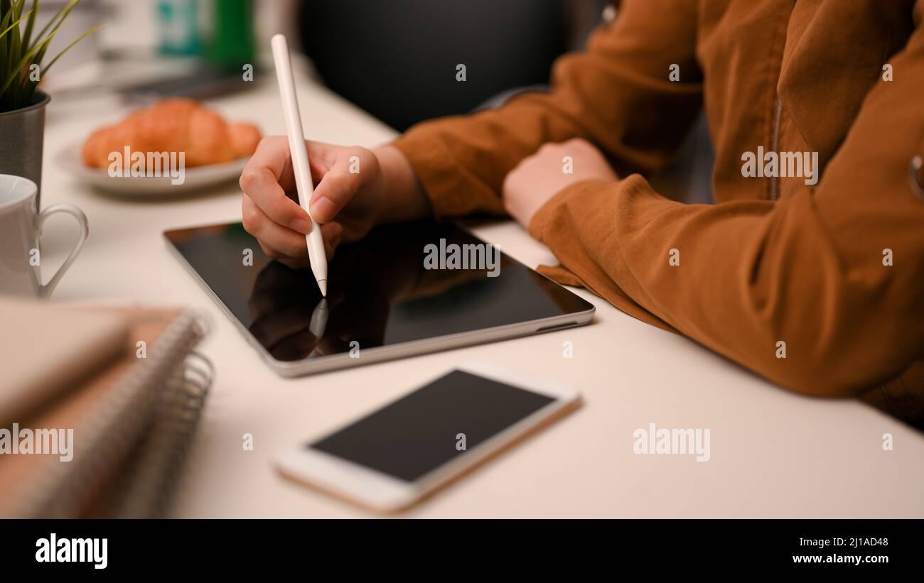 Side view, Female in brown shirt using stylus pen and digital tablet ...