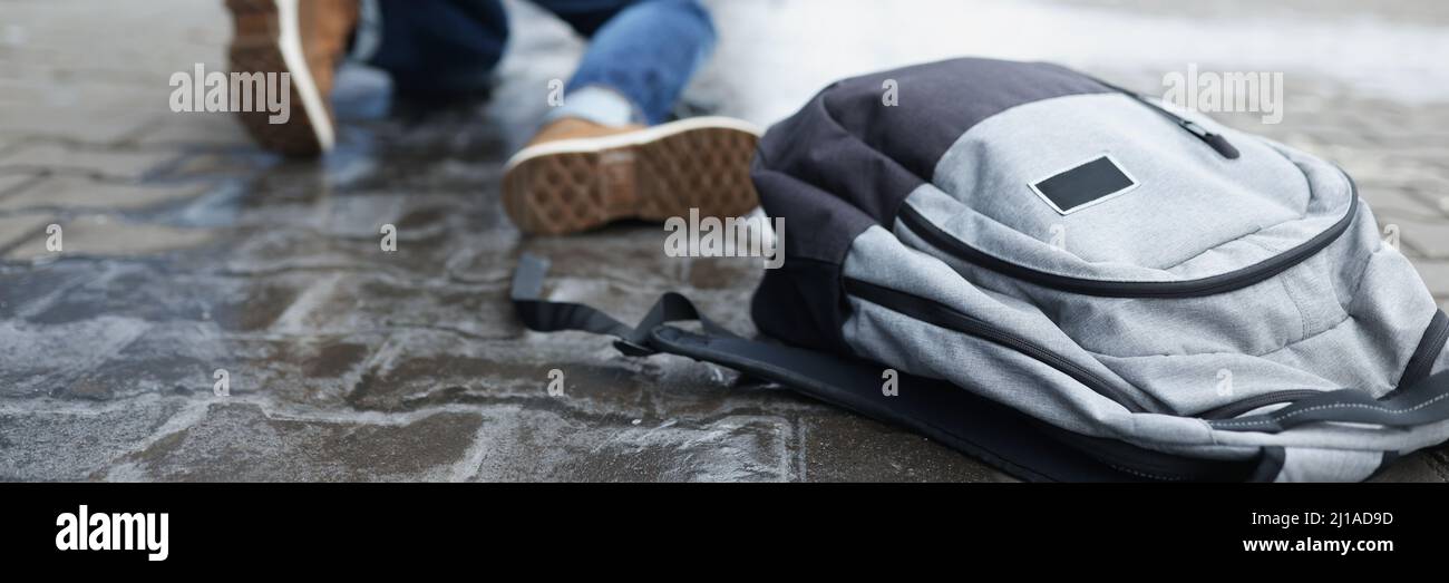 Backpack lying on slippery paving slabs near falling man closeup Stock ...