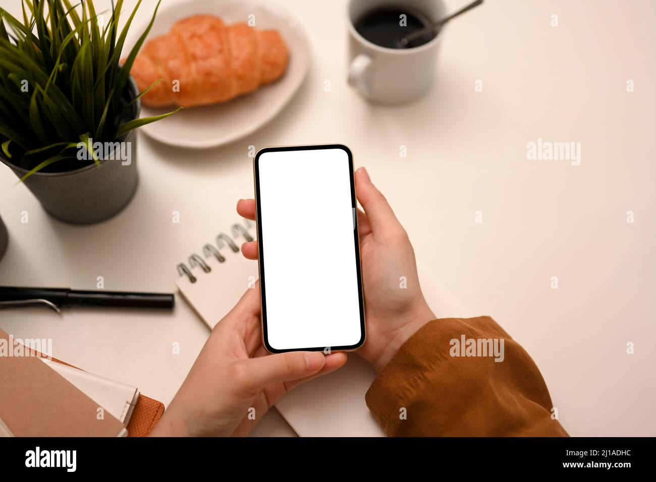 A smartphone white screen mockup in a women's hand over modern minimal ...