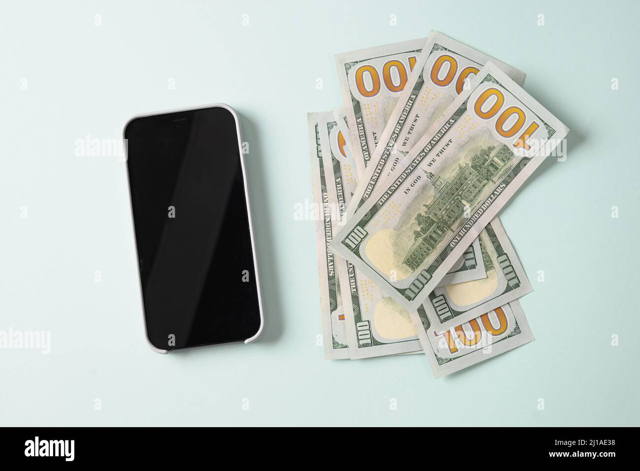 American 100 dollar bills and smartphone screen on blue background ...