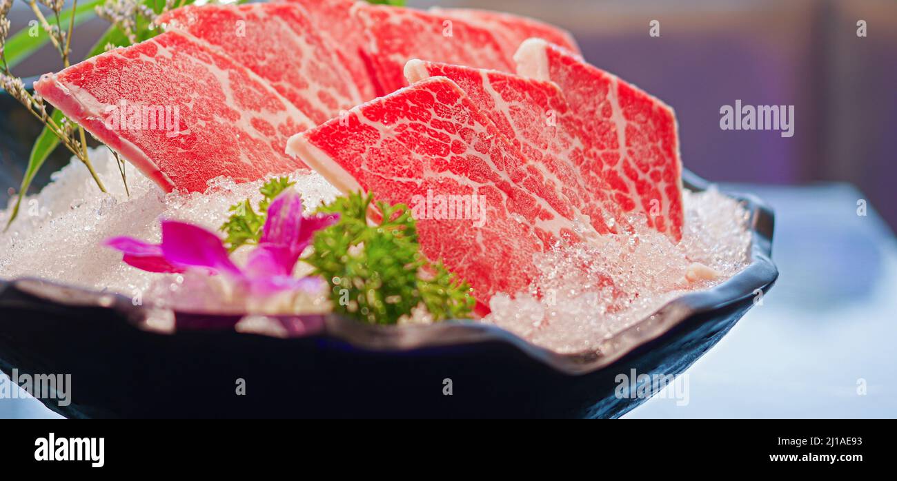 frozen raw wagyu beef slices for hot pot on ice in black bowl Stock ...