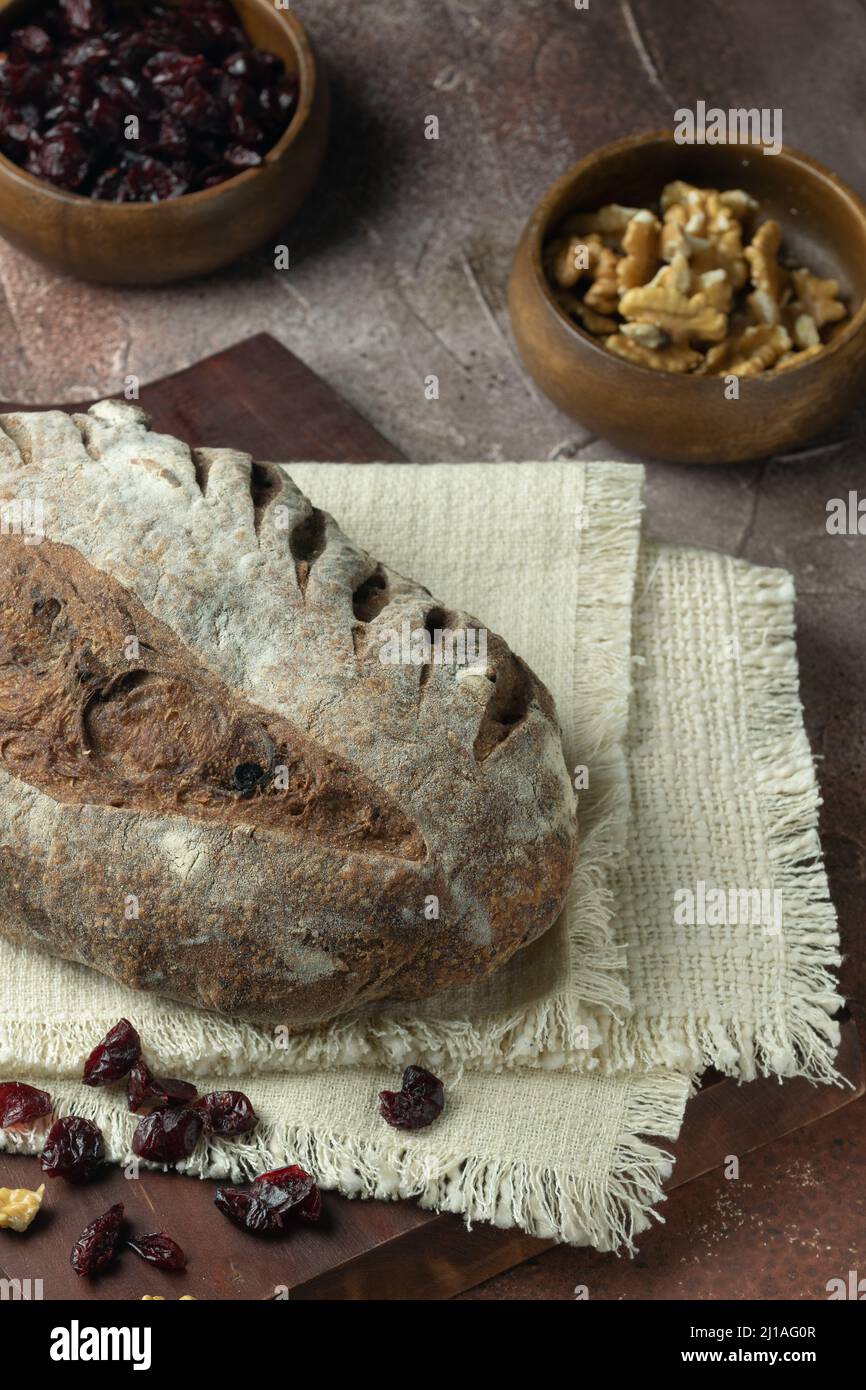 A vertical closeup of a loaf of rustic bread with nuts and raisins ...