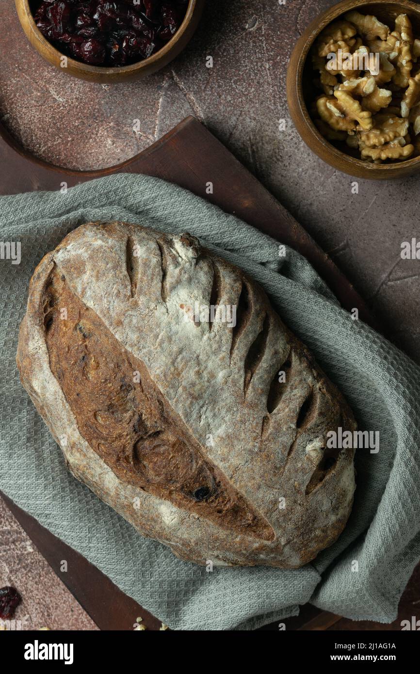 A vertical closeup of a loaf of rustic bread with nuts and raisins ...