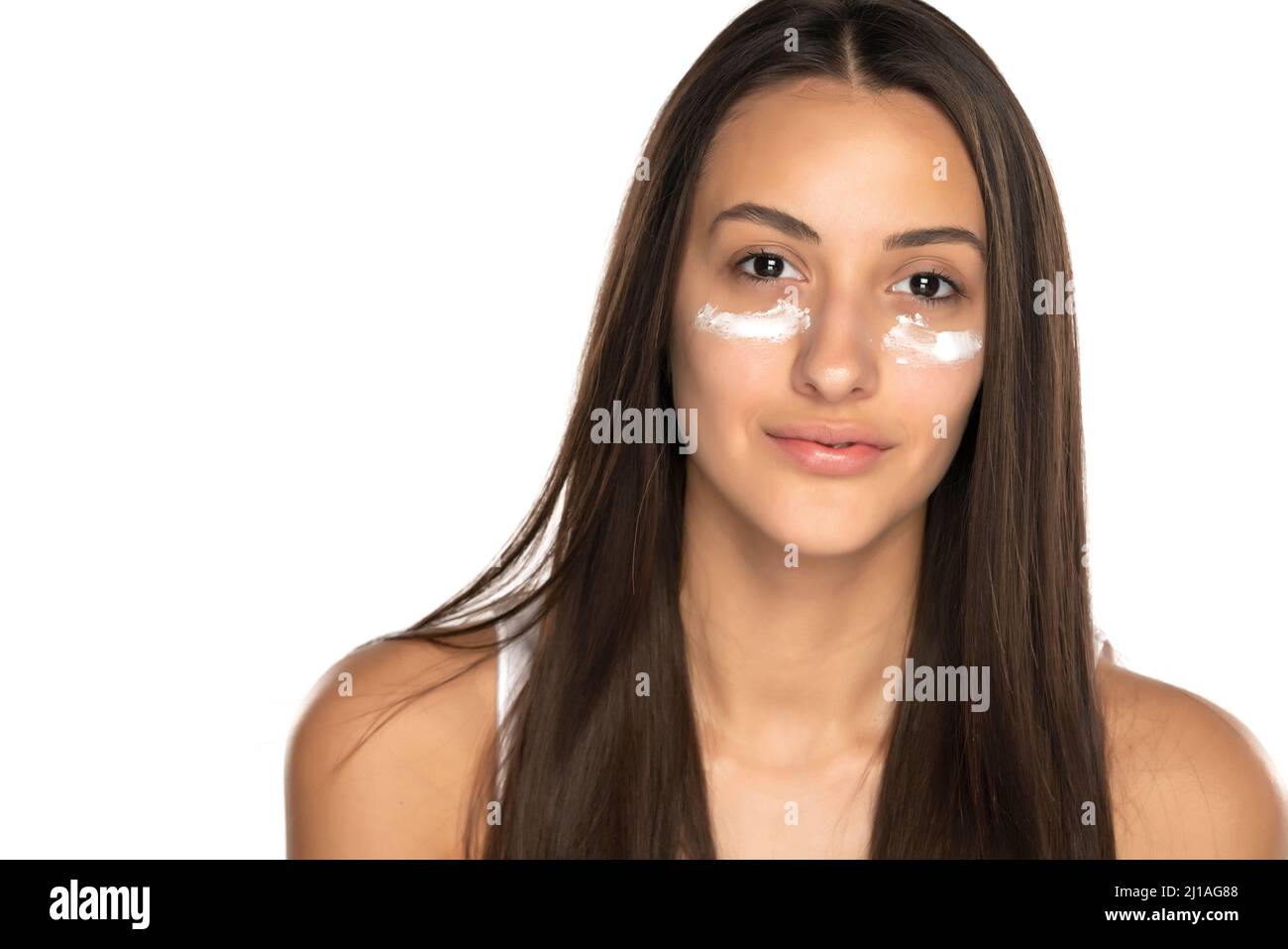 a young beautiful woman posing with facial cream under her eyes on a ...