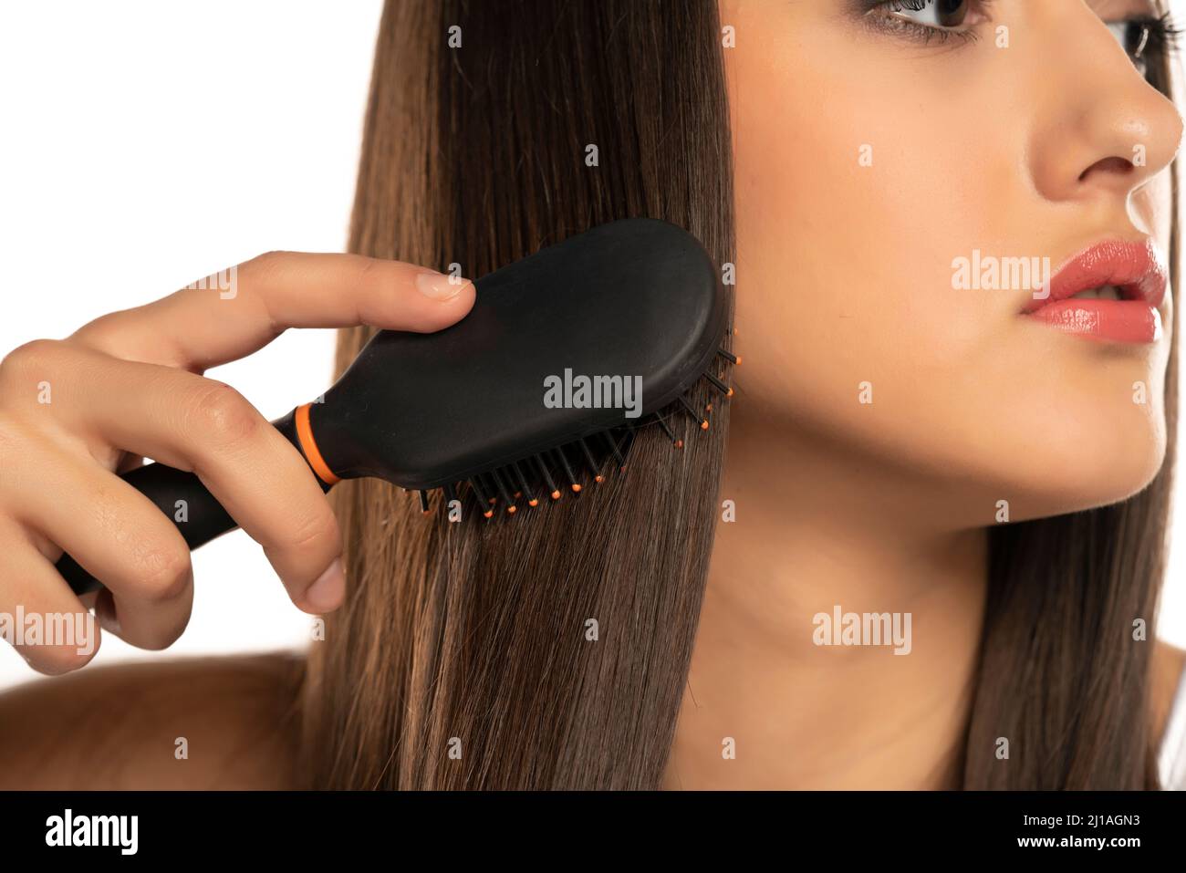 Close up of a young brushing her straight long hair on a white ...